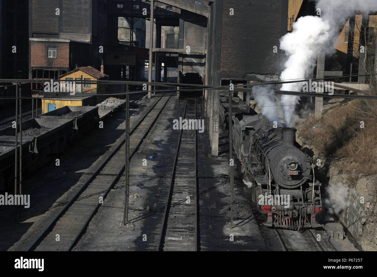 A rake of spoil wagons wait to be loaded behind a Chinese SY class ...