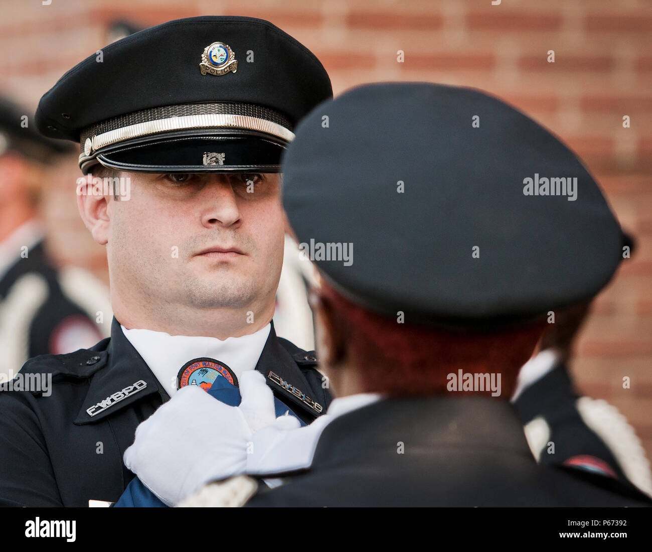 A police honor guard member carries the folded flag to the detail in ...
