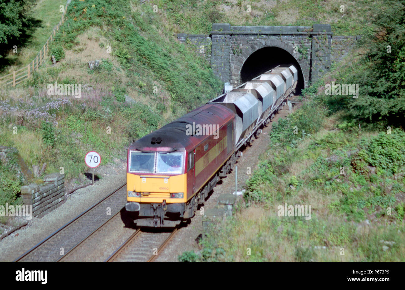 An EWS freight train exits a tunnel on the railway in the Peak District ...