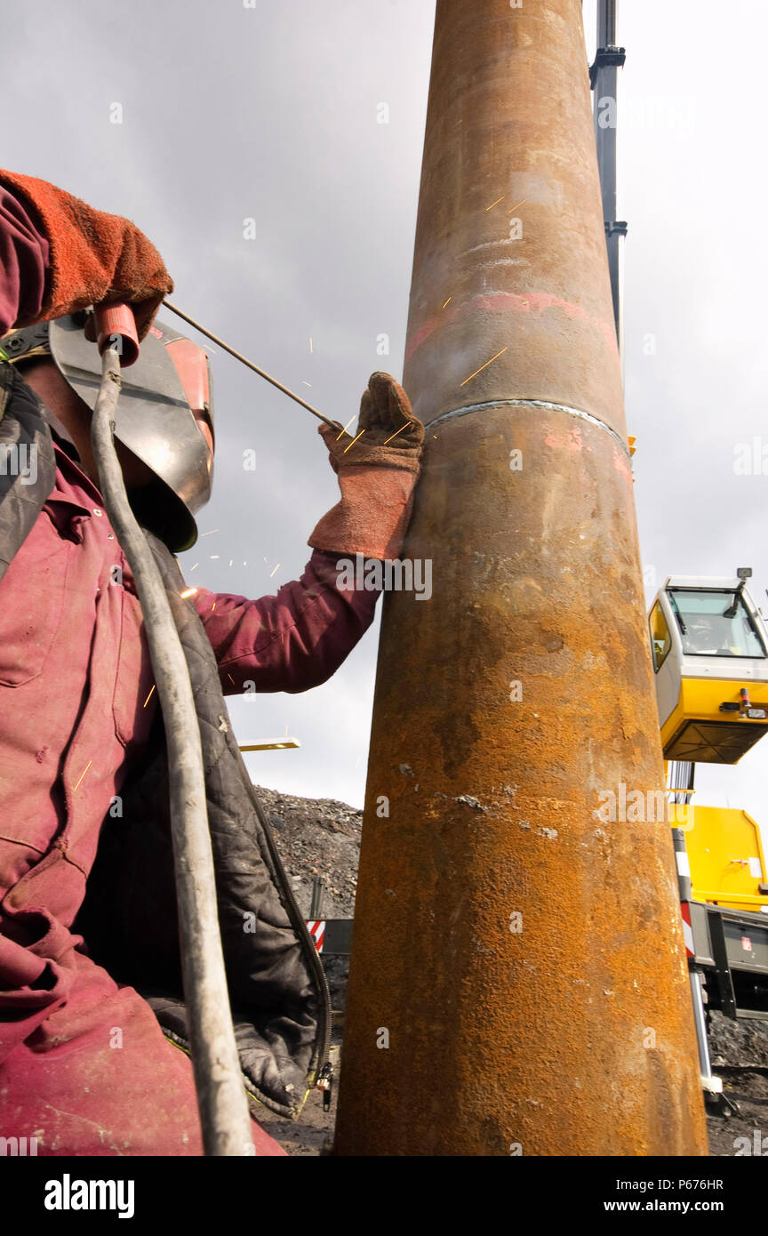 Welders joining 2 casings to be pile driven down to bed rock Stock ...