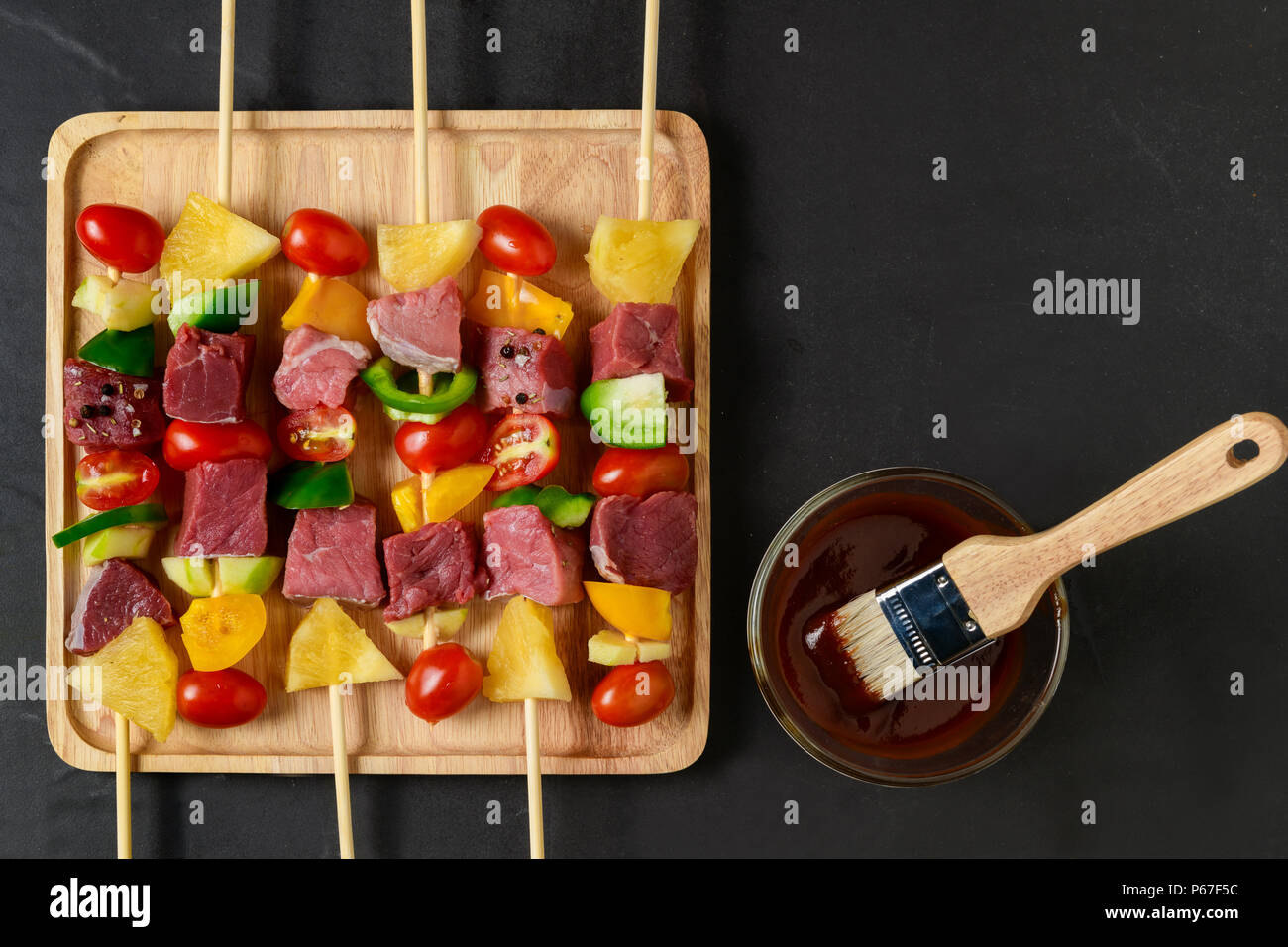 raw beef barbecue with vegetables on wood plate and barbecue sauce ...