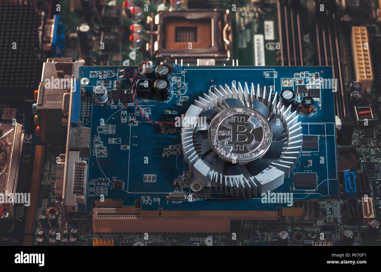 Silver Bitcoin on the top of blue graphic card as cryptocurrency mining ...