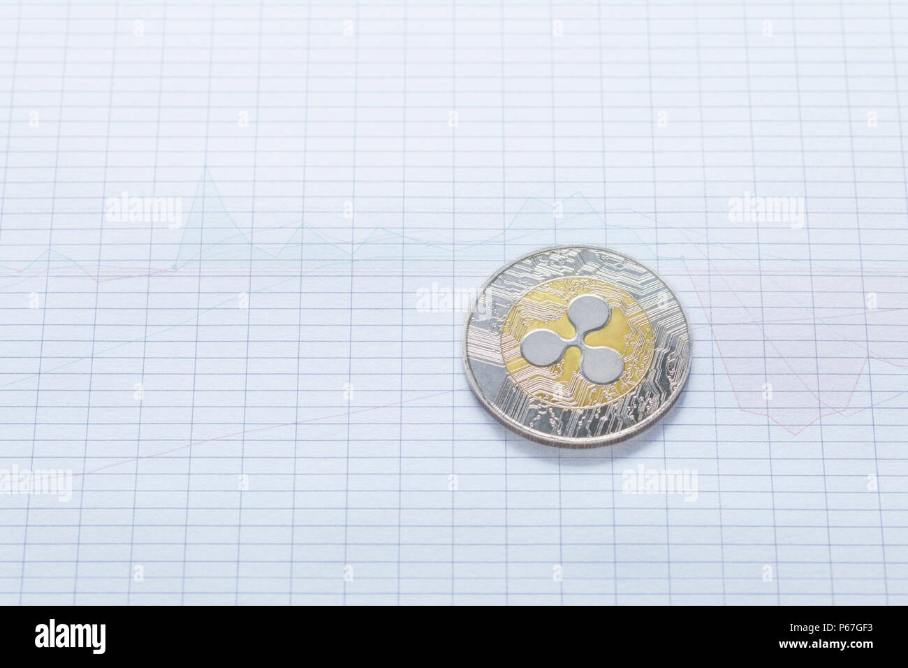 Silver-gold Ripple coin laid on decreasing chart of value as ...