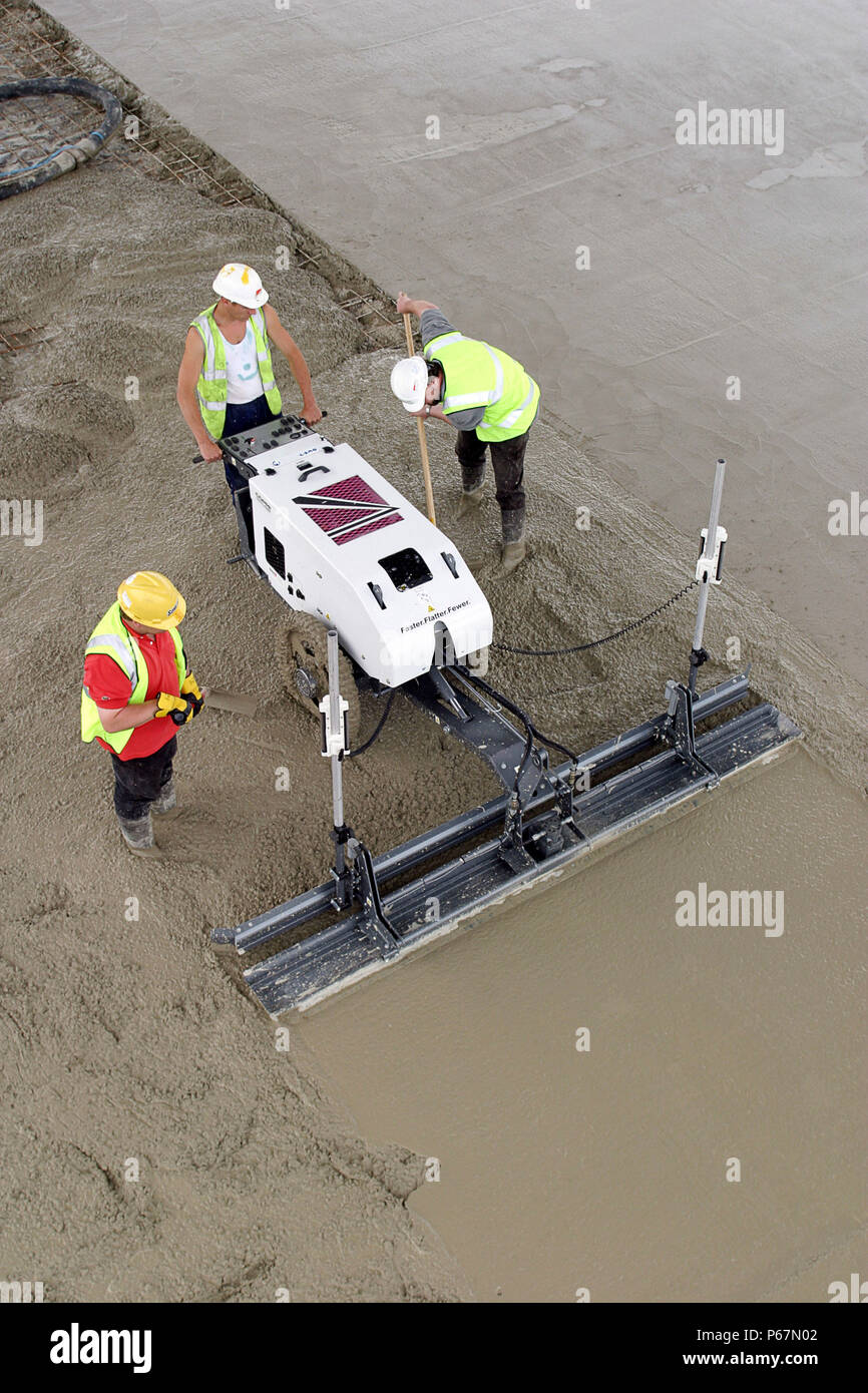 Construction workers using a concrete compactor smoothing concrete ...