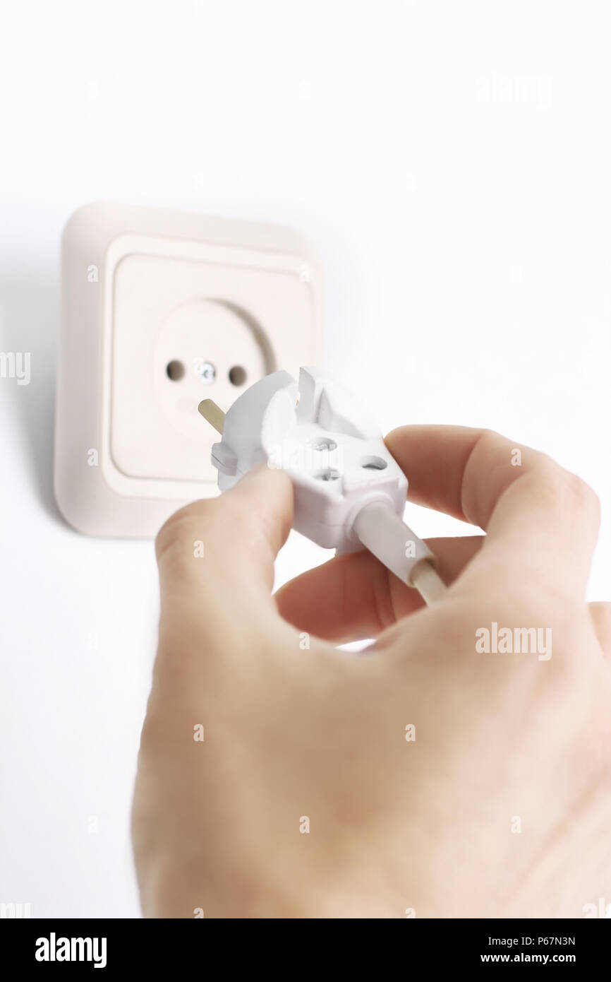 Hand inserting green electrical plug into outlet Stock Photo - Alamy