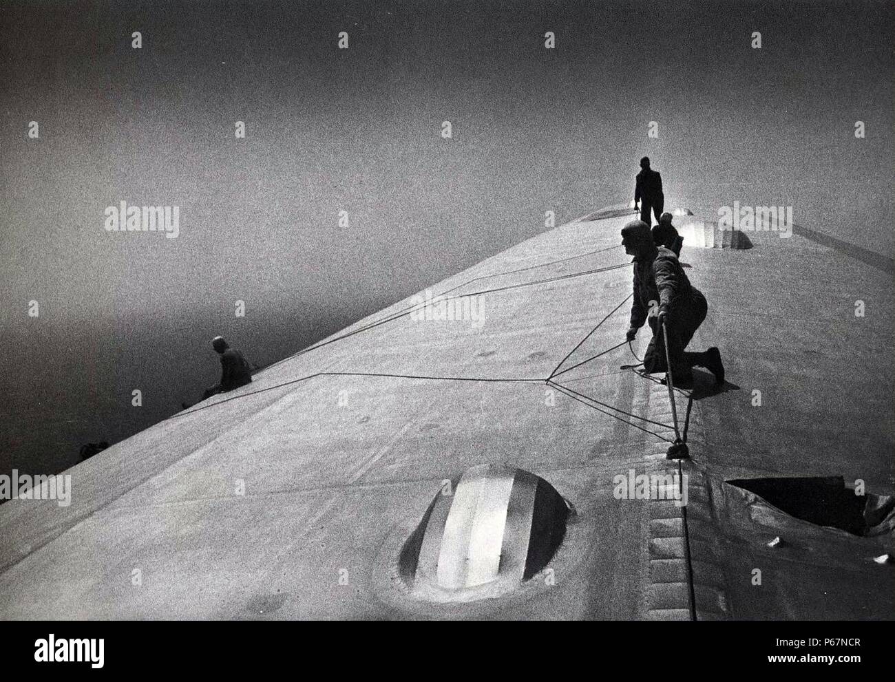 Image shows maintenance crewmen repairing a Zeppelin mid-flight. The ...