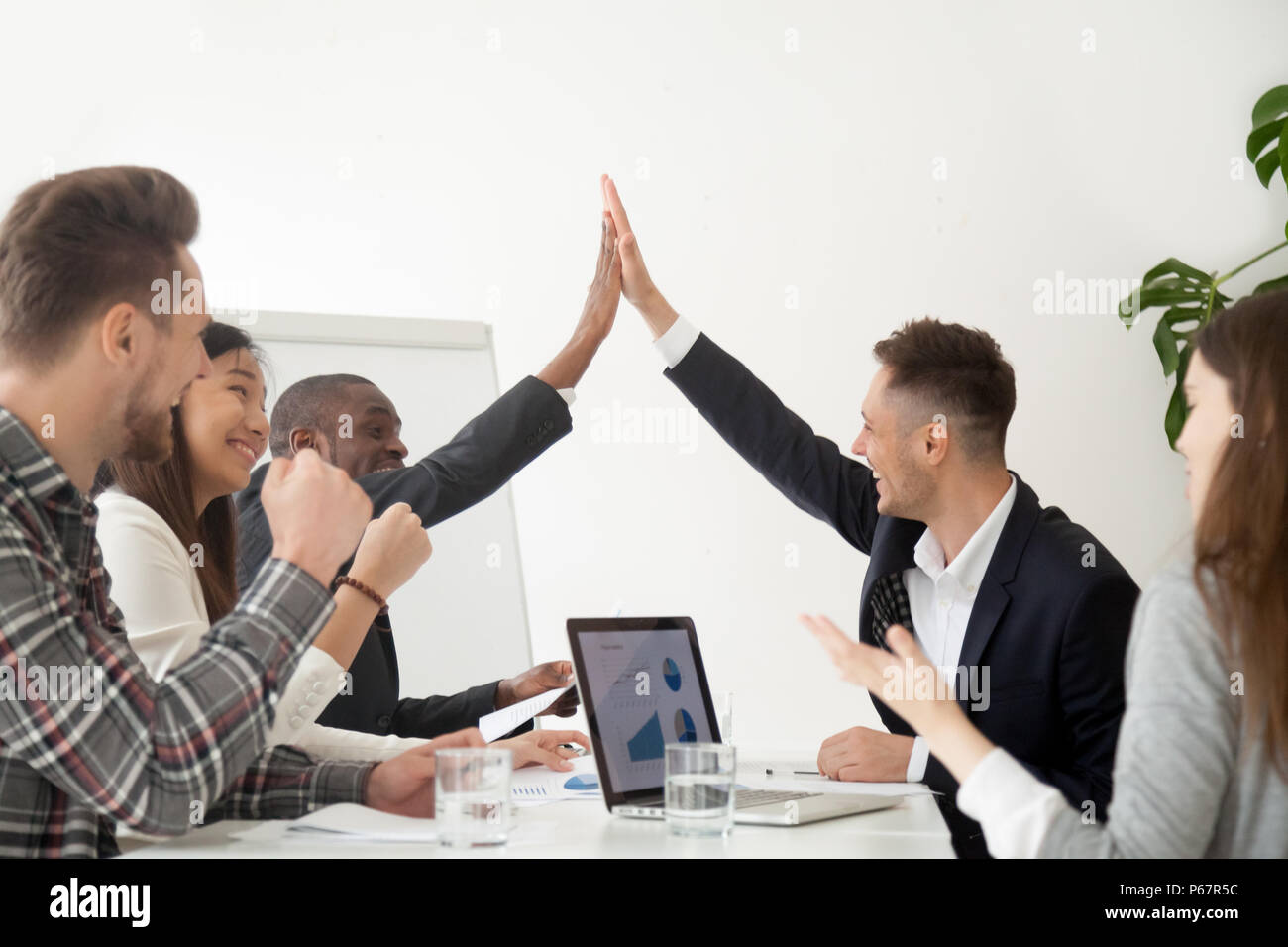 Smiling colleagues giving high five excited by business results Stock ...
