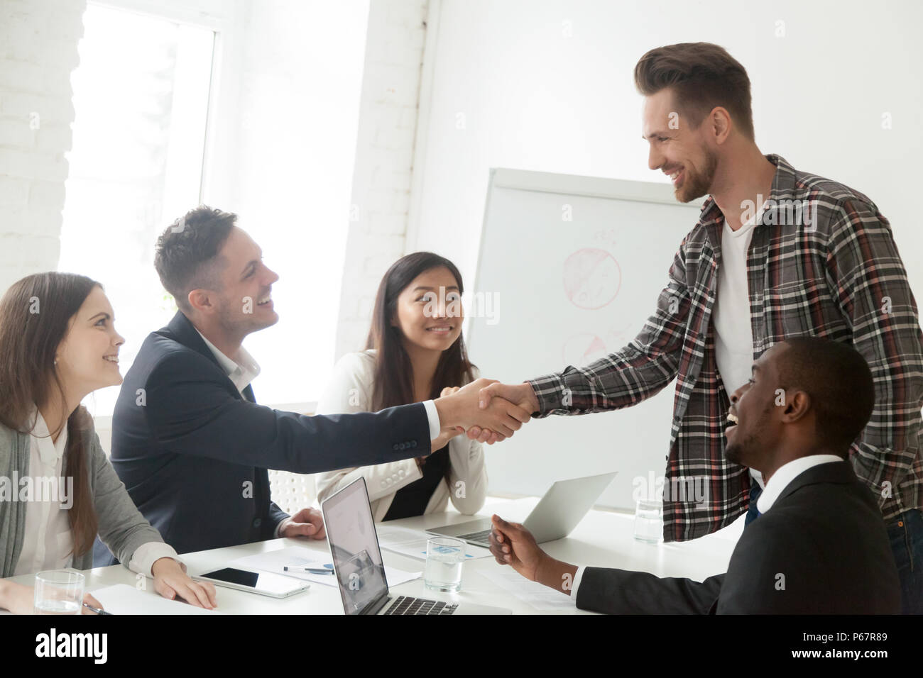 Team leader handshaking new member to diverse work group Stock Photo ...