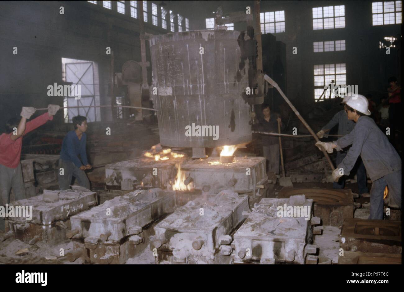 Pouring liquid metal into the moulds for casting componant parts for ...