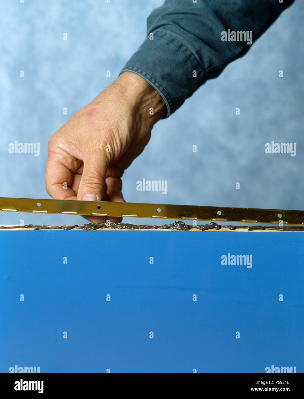Close-up of hand attaching hinge to blue shutter FOR EDITORIAL USE ONLY ...