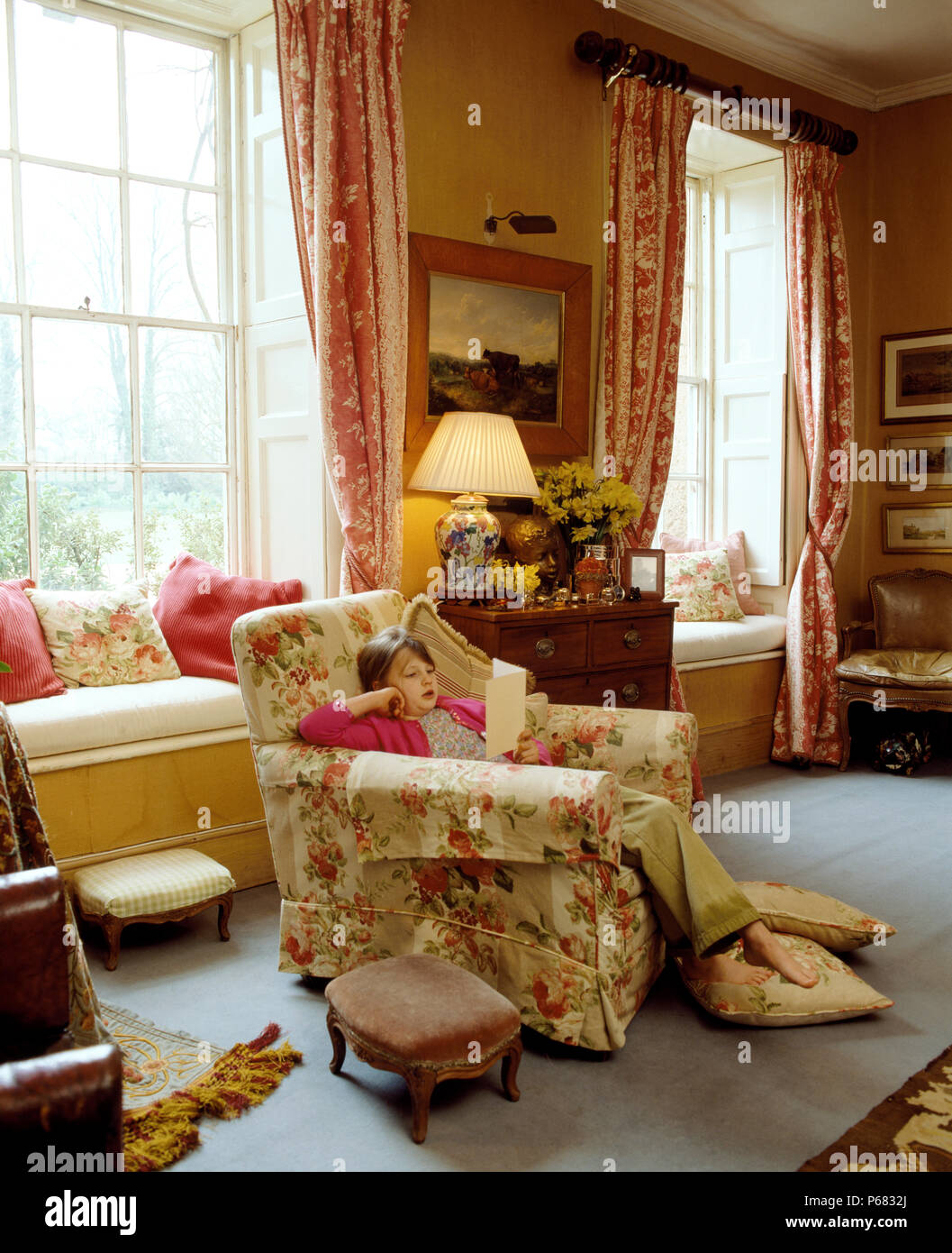 Girl sitting and reading in armchair in country living room FOR ...