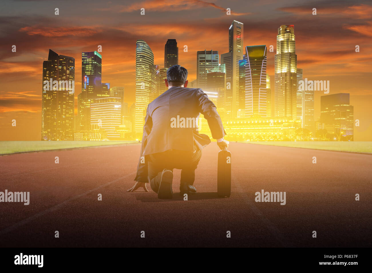 Businessman on a track ready for race in business on blurred city ...