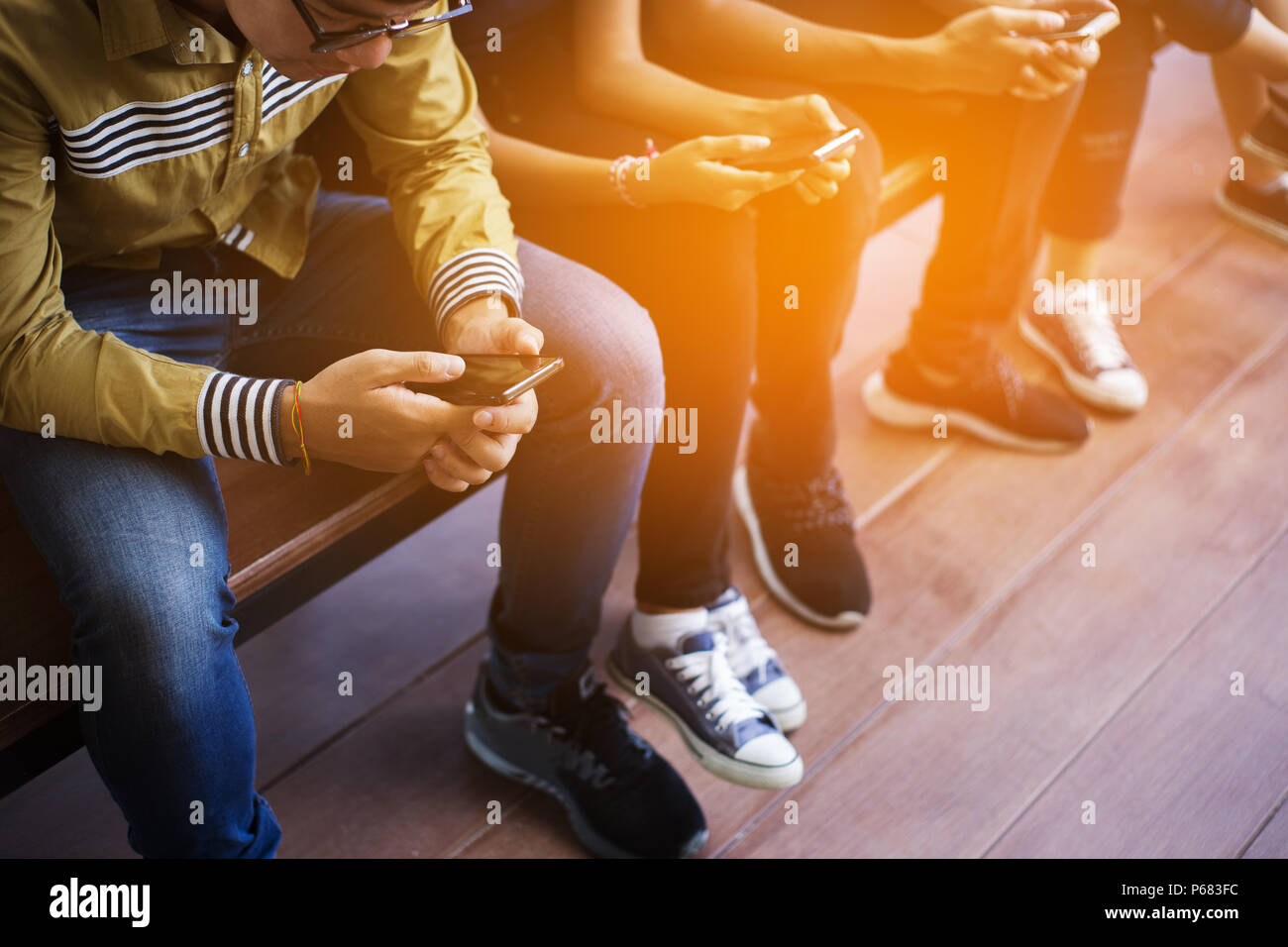 Summer sunny day, Close-up of smartphones in the hands of man sitting outdoors on wooden steps ...