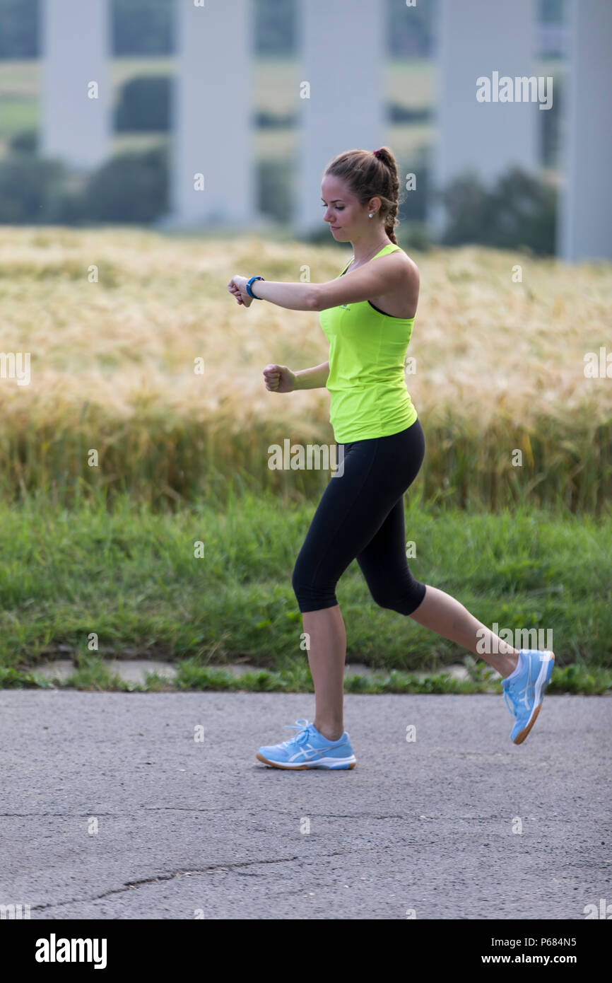 Young woman jogging, running, checking her vital signs on a fitness ...