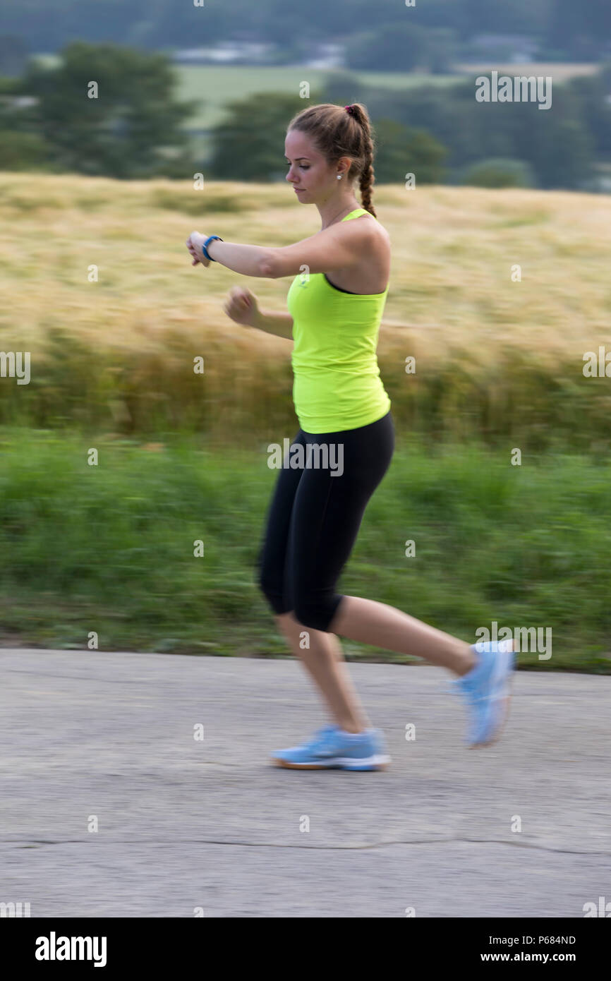 Young woman jogging, running, checking her vital signs on a fitness ...