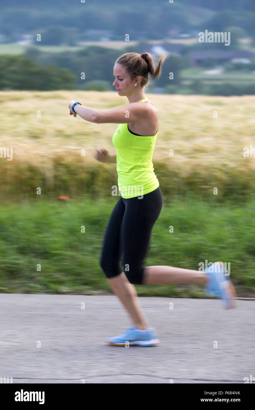 Young woman jogging, running, checking her vital signs on a fitness ...