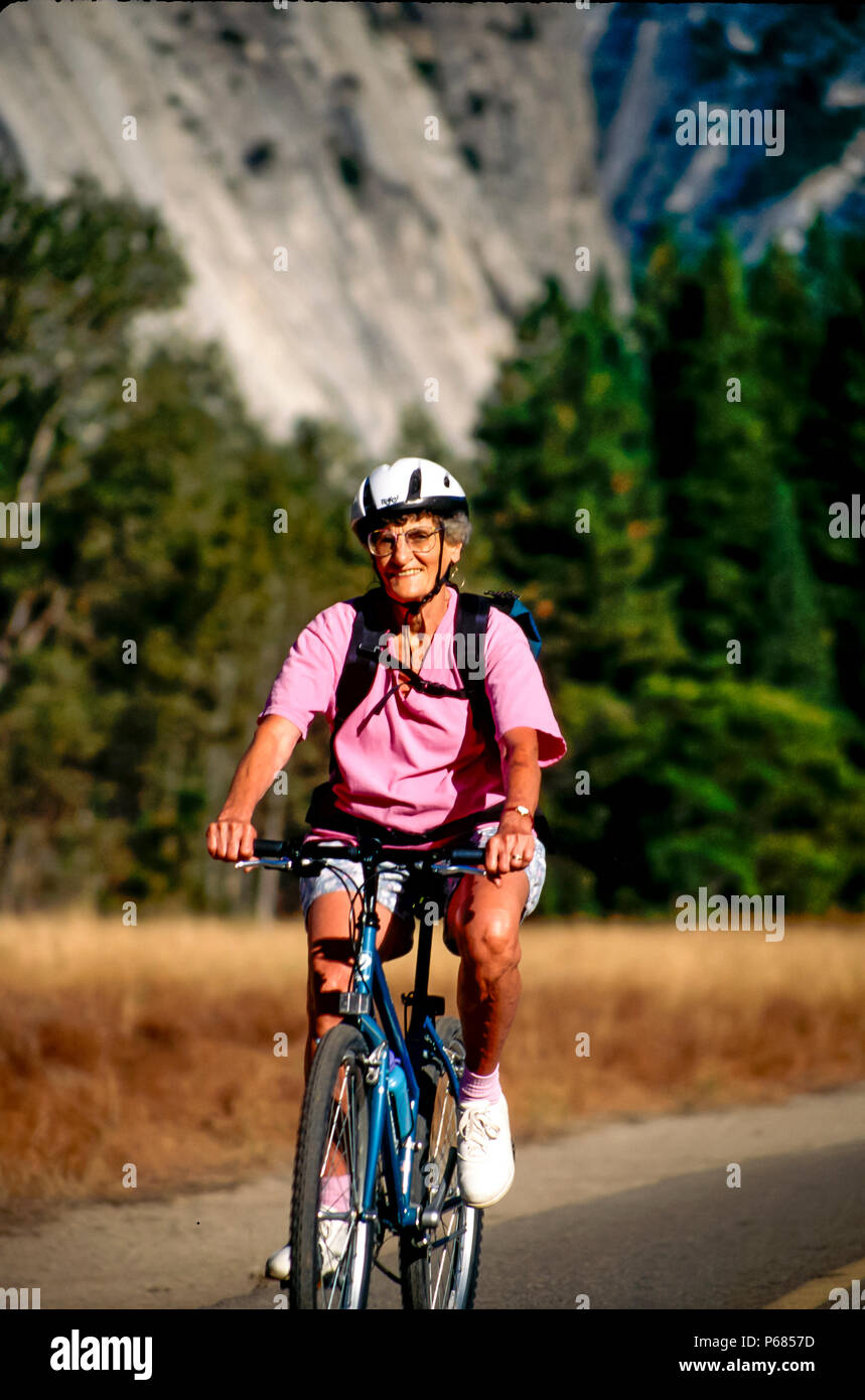 Senior mature woman riding bicycle through Yosemite National Park MR ...