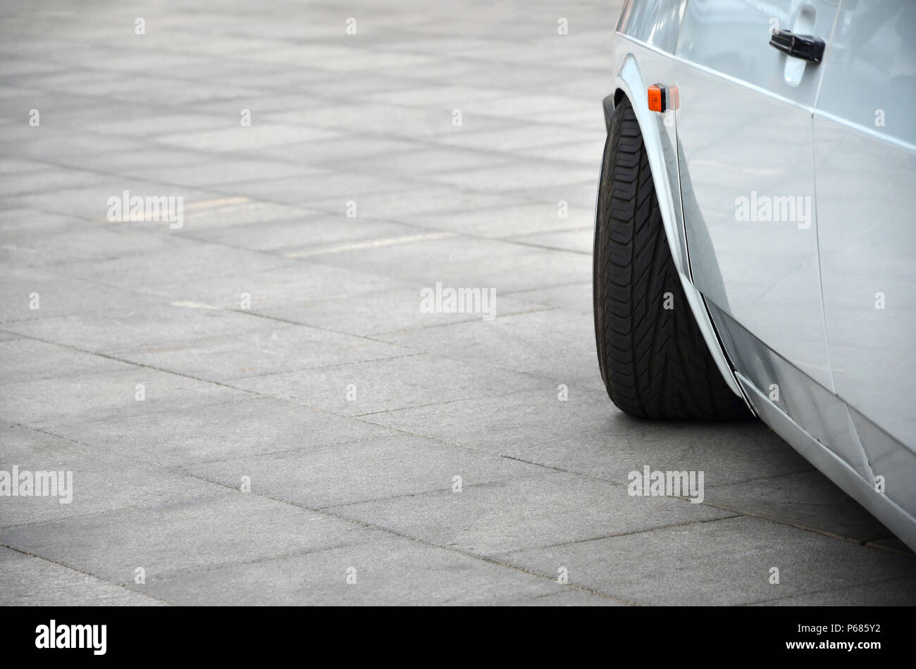 Diagonal view of a white glossy car that stands on a square of gray ...
