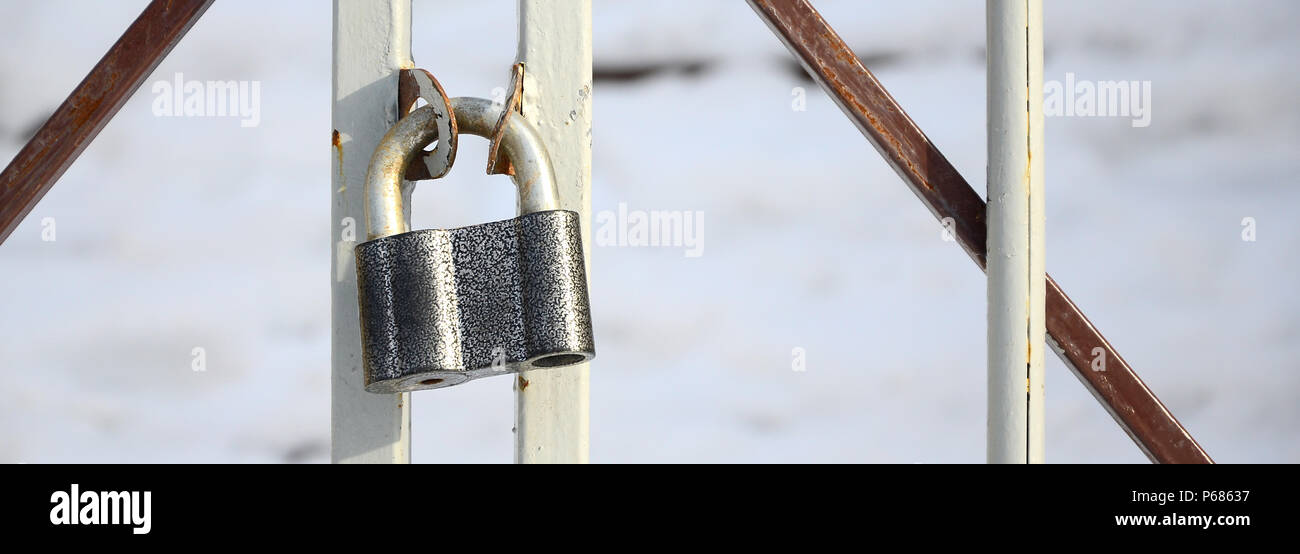 A large gray padlock hangs on a metal gate Stock Photo - Alamy