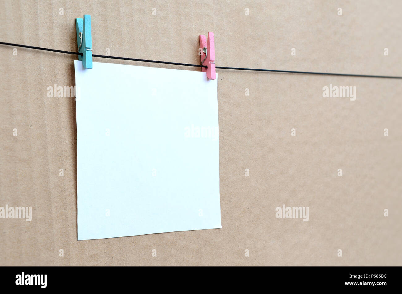 White blank card on rope on a brown cardboard background. Creative ...
