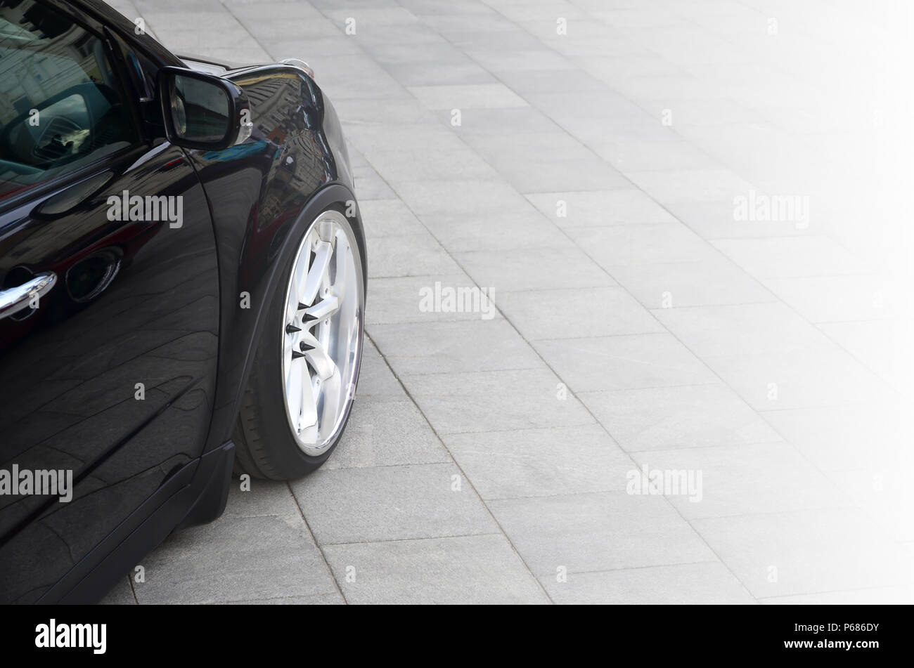 Diagonal view of a black glossy car with white wheels, which stands on ...