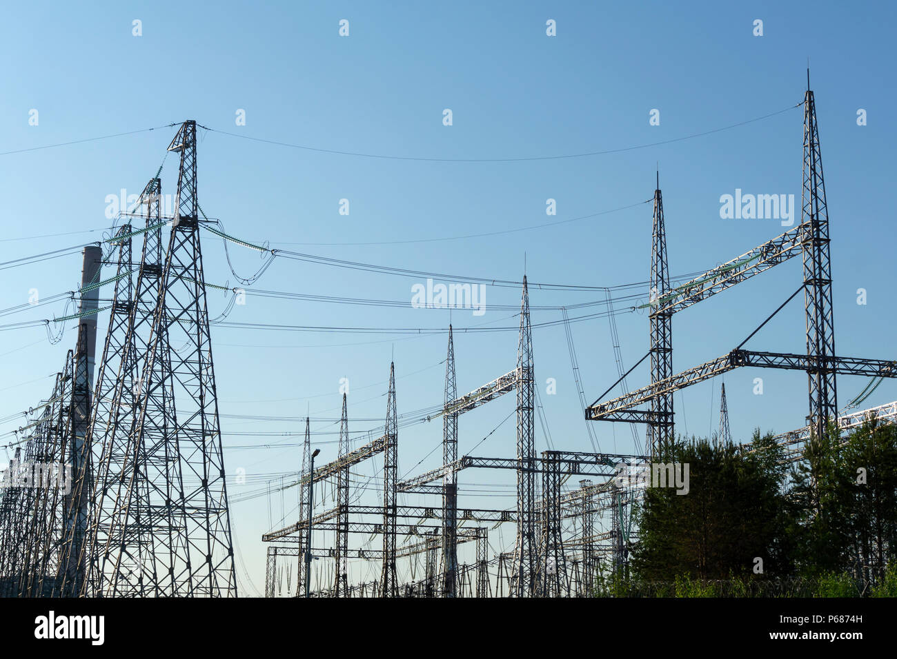 Power line pylons leading from an electrical substation against a blue ...