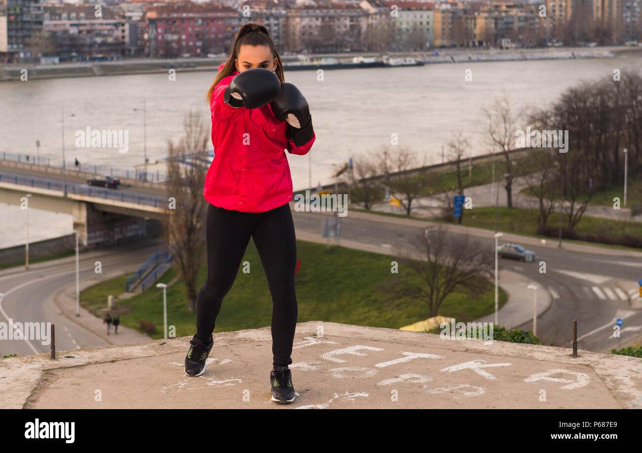 Young pretty girl wearing boxing gloves throwing a punch - martial arts ...