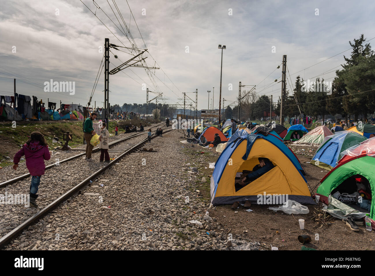 Refugees in tents next to railway tracks in a makeshift camp at the ...