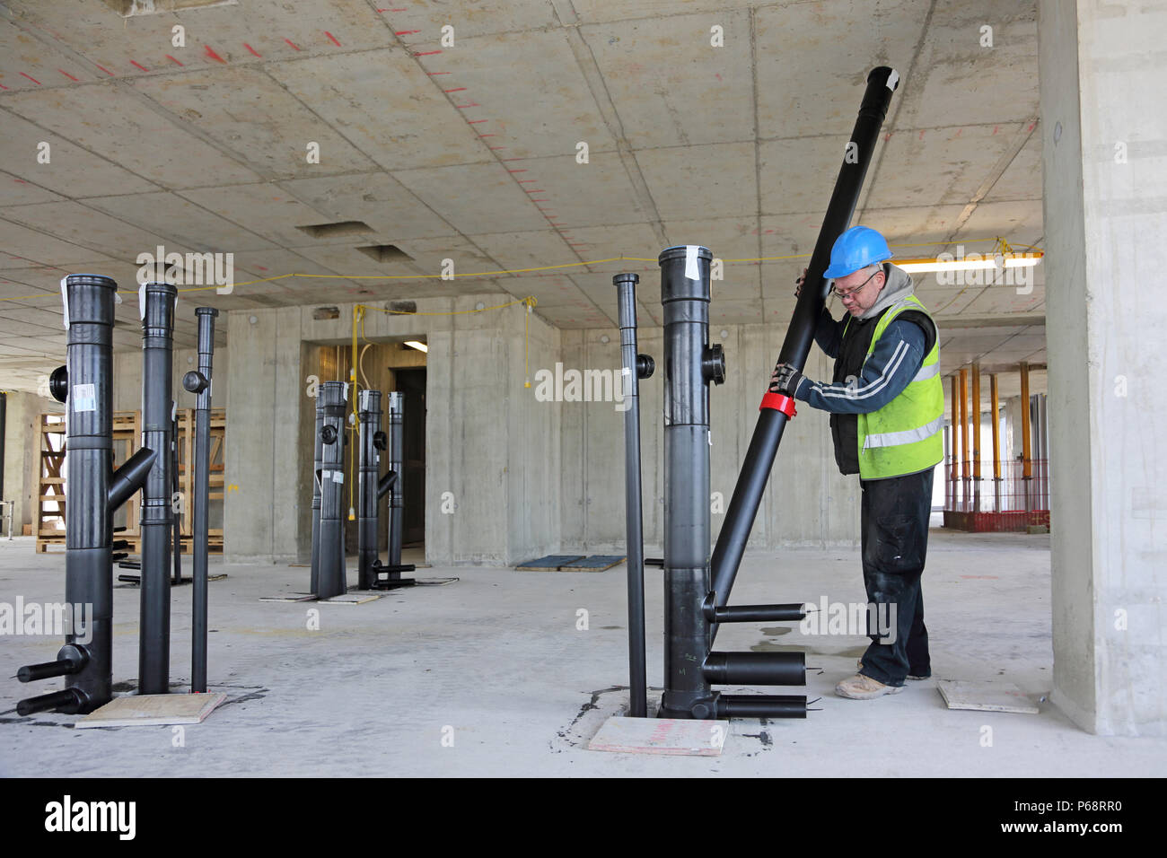 A workman installs plastic soil and waste drainage pipes in a new ...