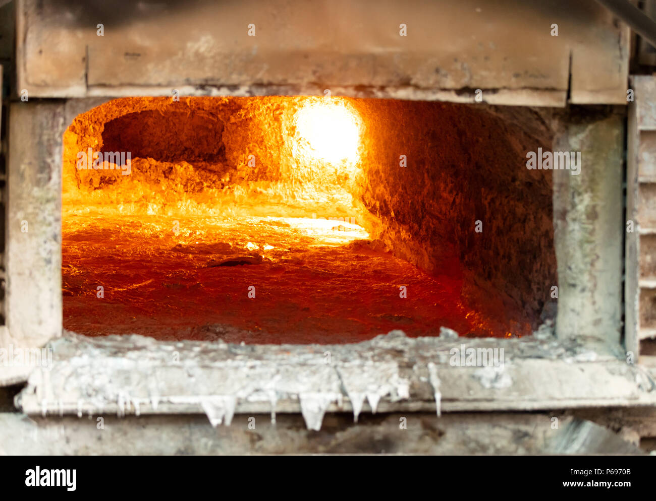 looking inside an aluminum melting furnace, in a foundry, with liquid ...