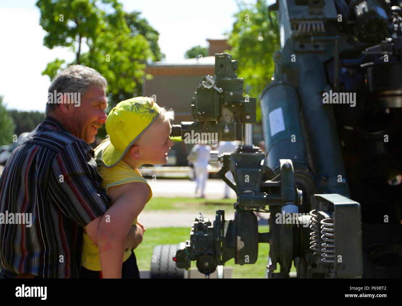 A Latvian father holds his son up so that he may look into the M137 A2 ...