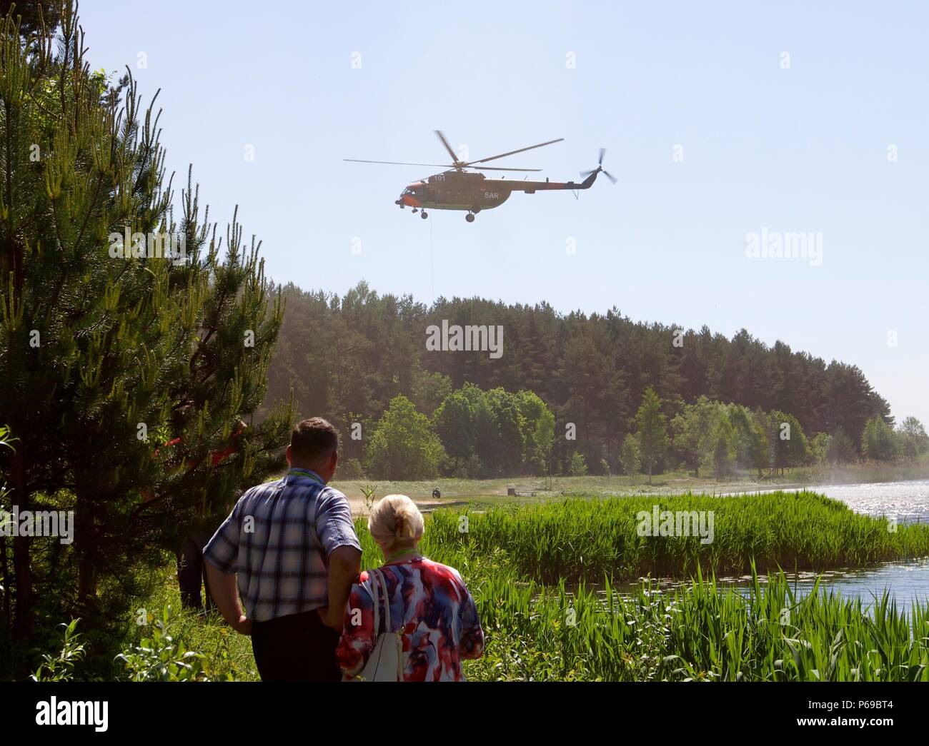 A Latvian family looks on as Mil Mi-2 helicopter hovers over the lake ...