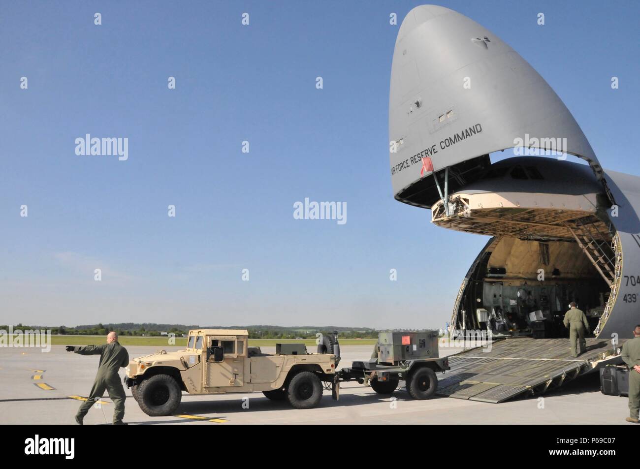 A 439th Airlift Wing Flight Crew member directs the unloading of a ...