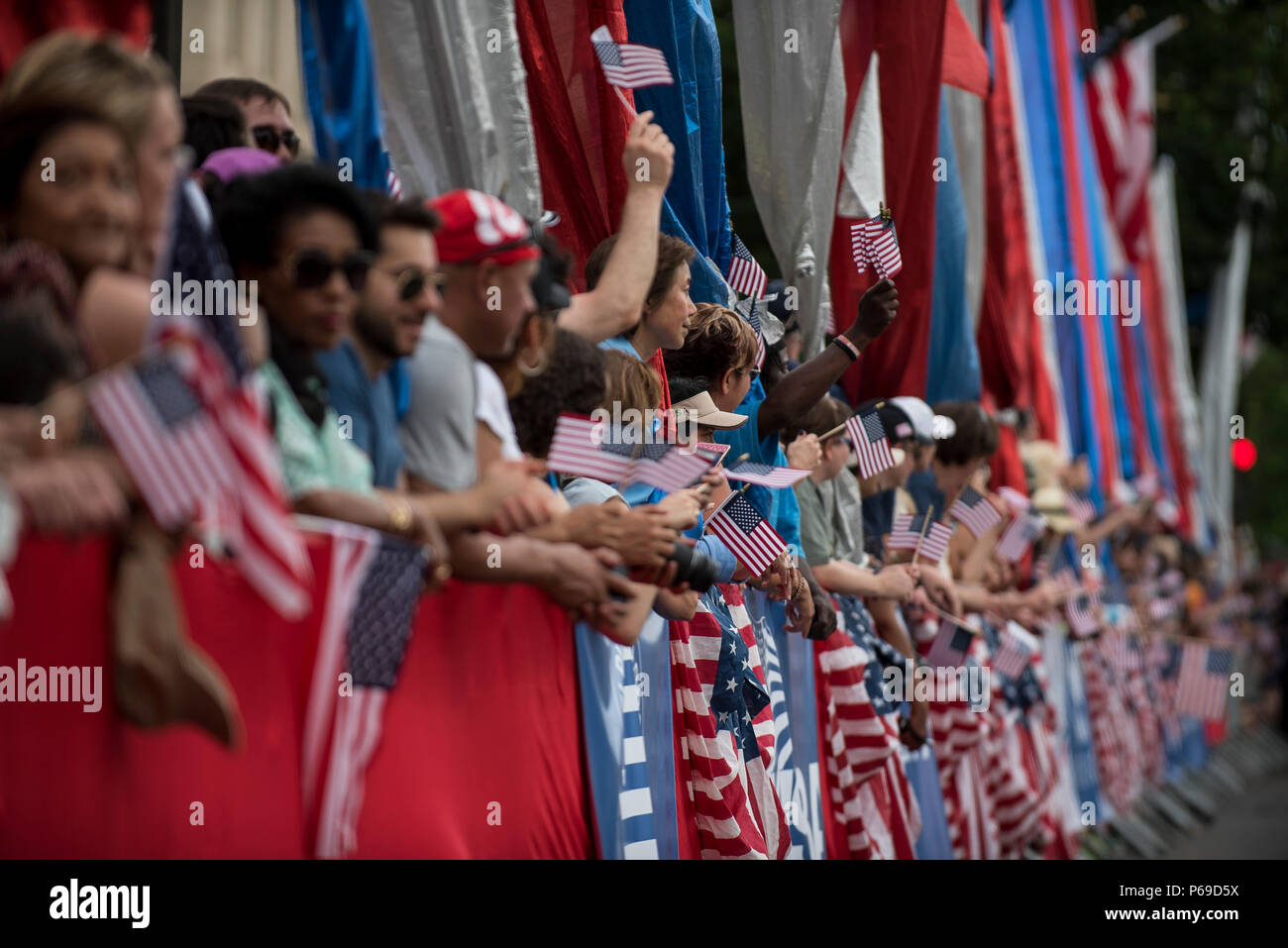 A crowd of supporters and observers wave American flags and cheer on ...