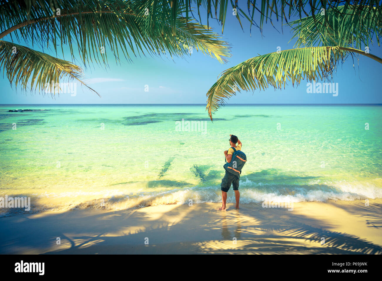 Young traveler man with backpack staying alone at seaside and looking ...