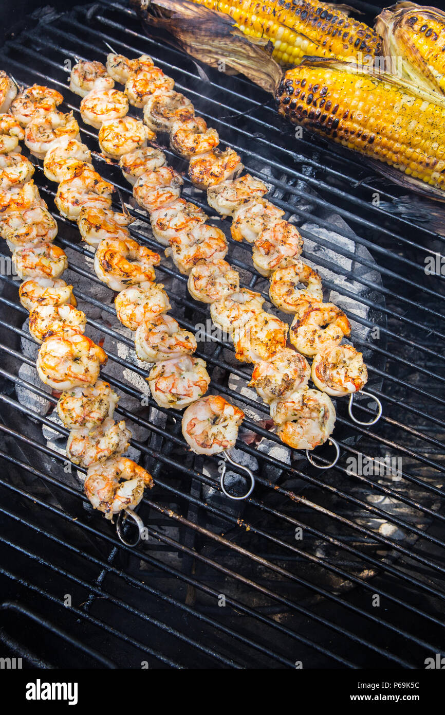 Shrimp skewred and yellow corn cooking on a outdoor charcoal barbecue ...