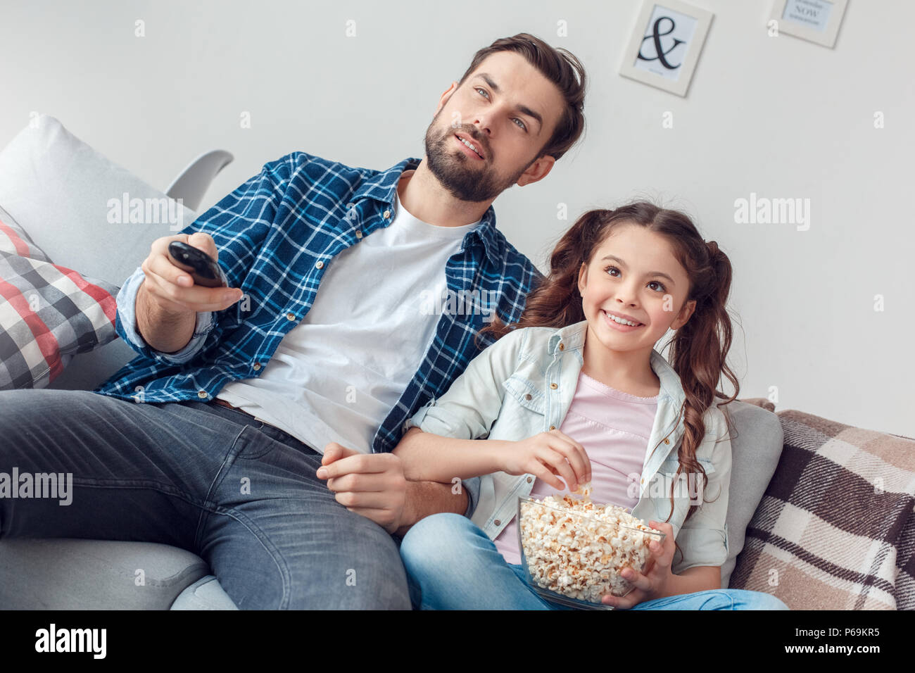Father and little daughter at home sitting watching movie eating ...