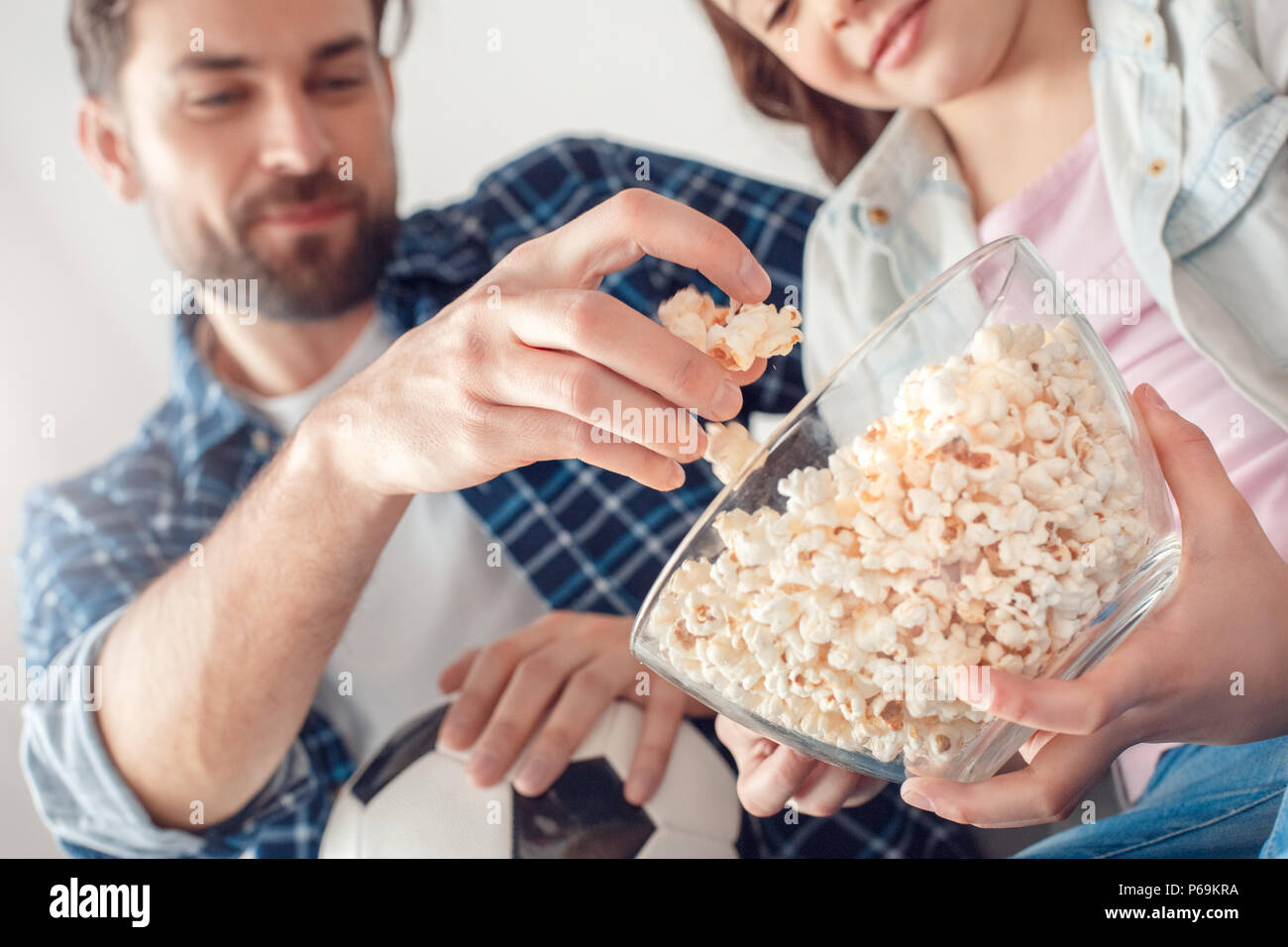 Father and little daughter at home sitting man taking popcorn from bowl ...