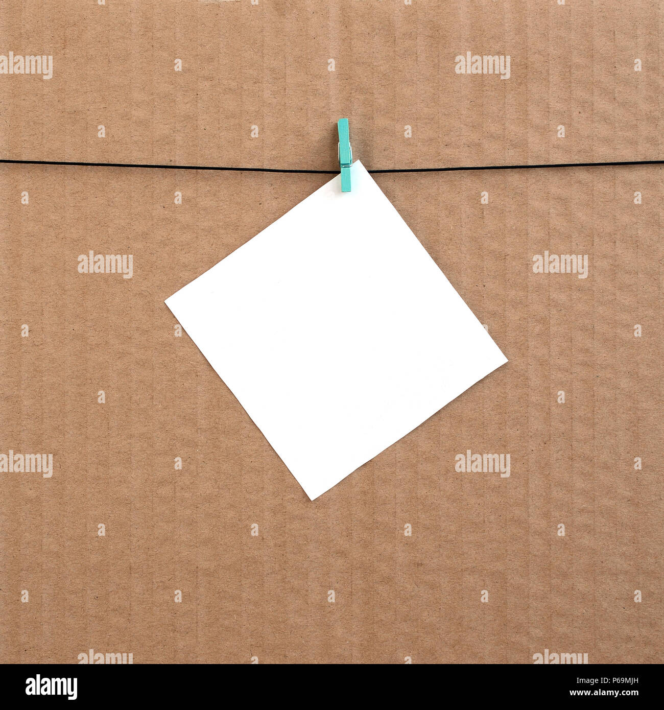 White blank card on rope on a brown cardboard background. Creative ...