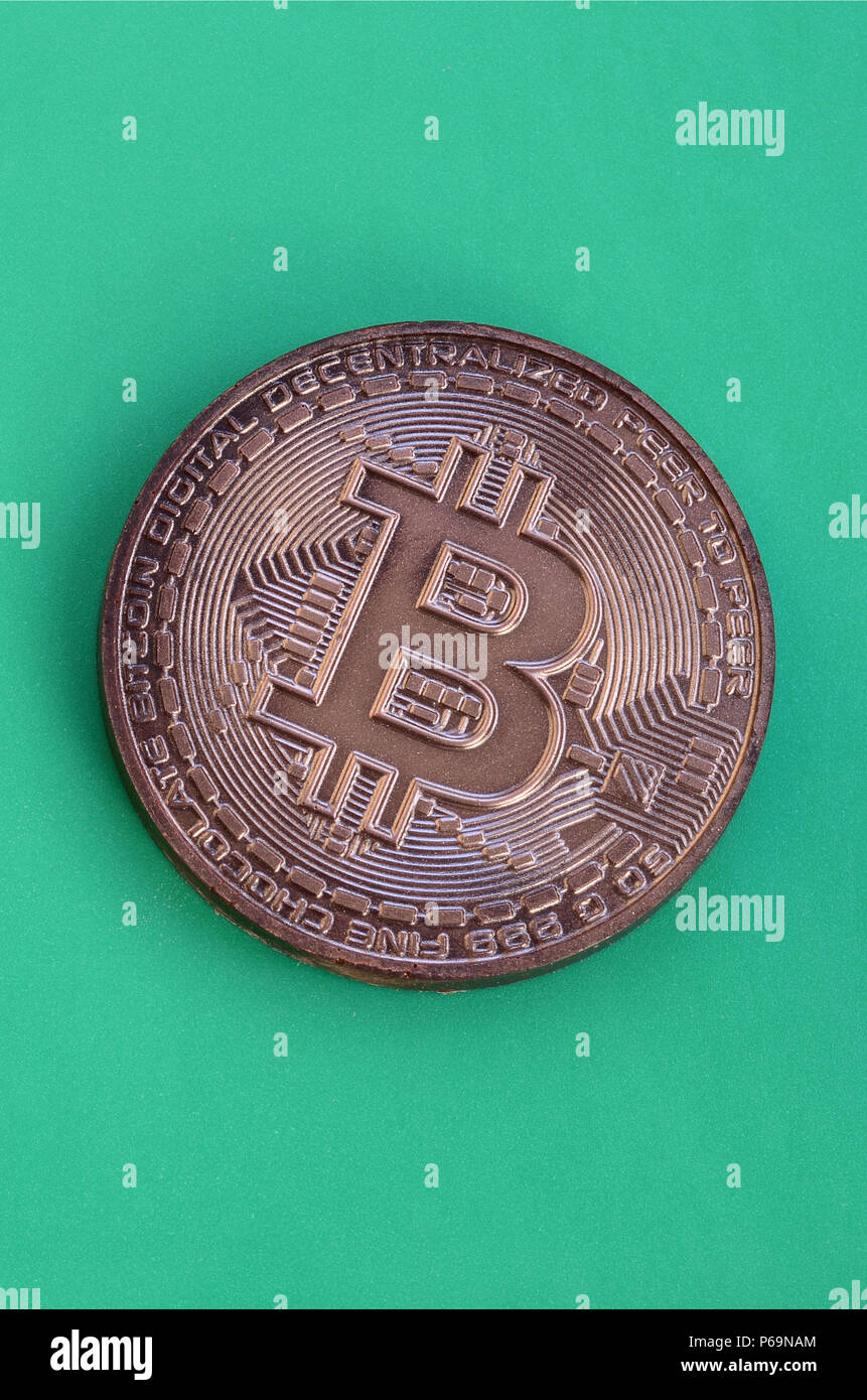 Chocolate product in the form of physical bitcoin lies on a green ...