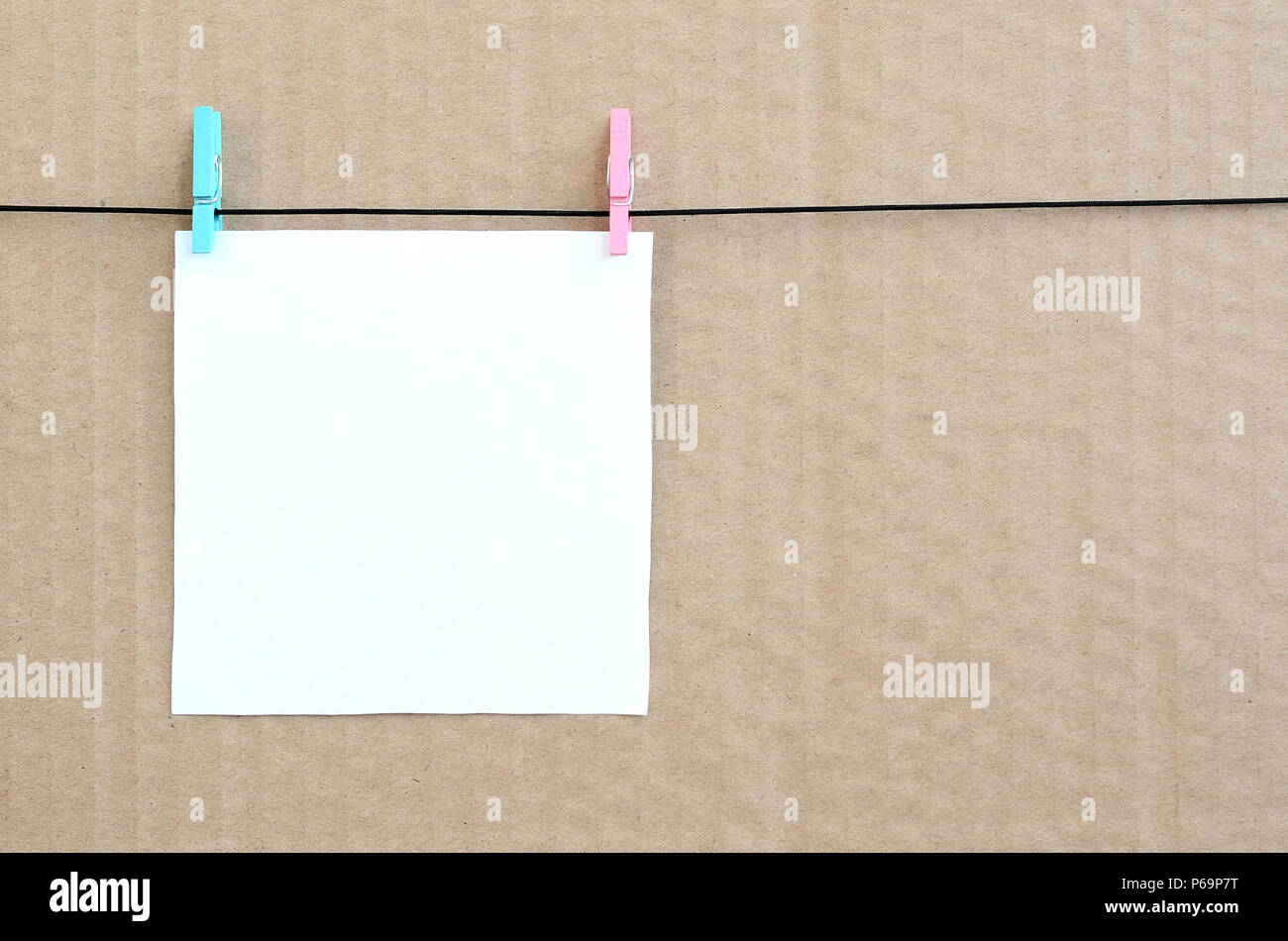 White blank card on rope on a brown cardboard background. Creative ...
