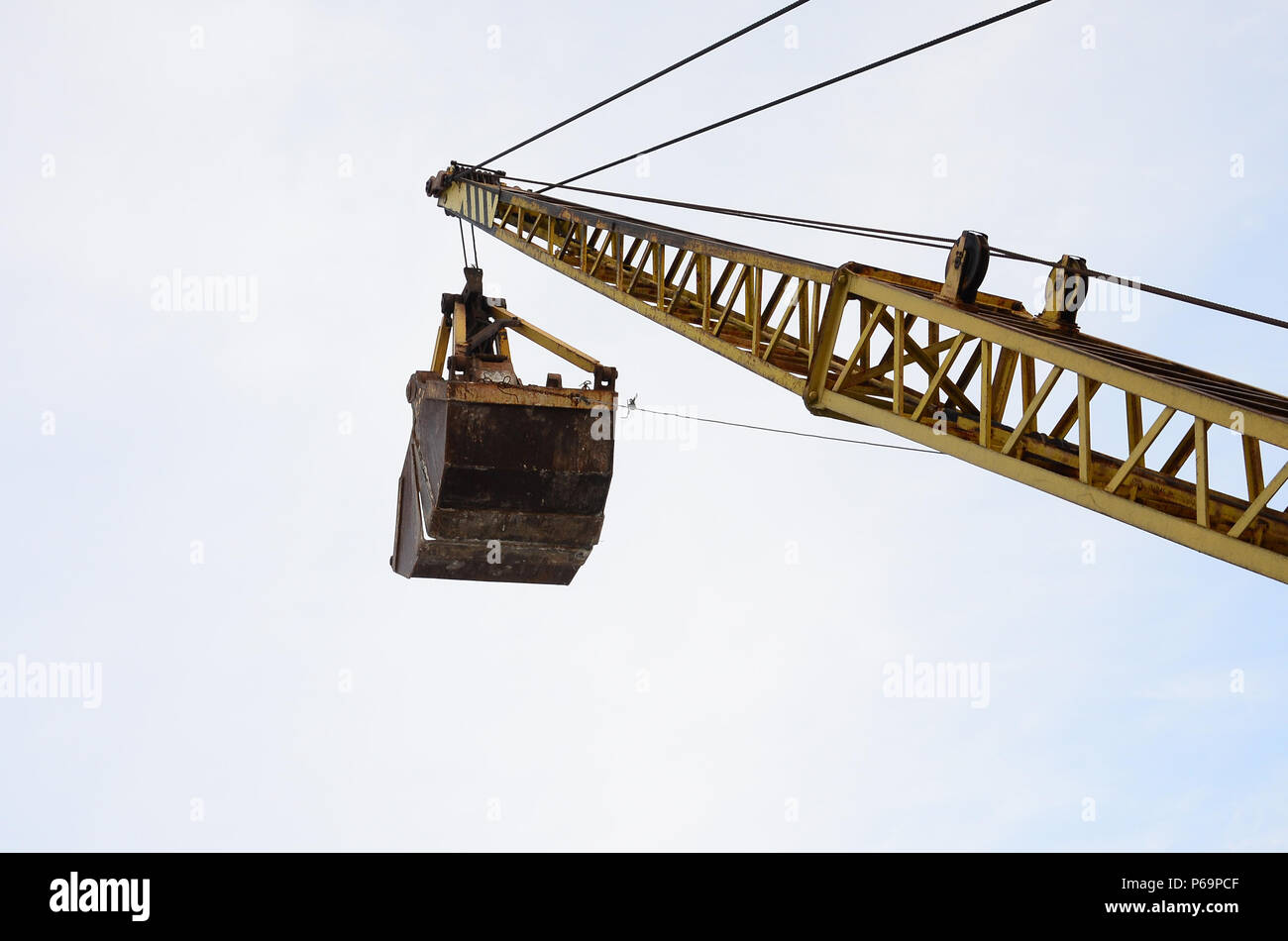 Old yellow mechanical clamshell grab on blue sky background Stock Photo ...