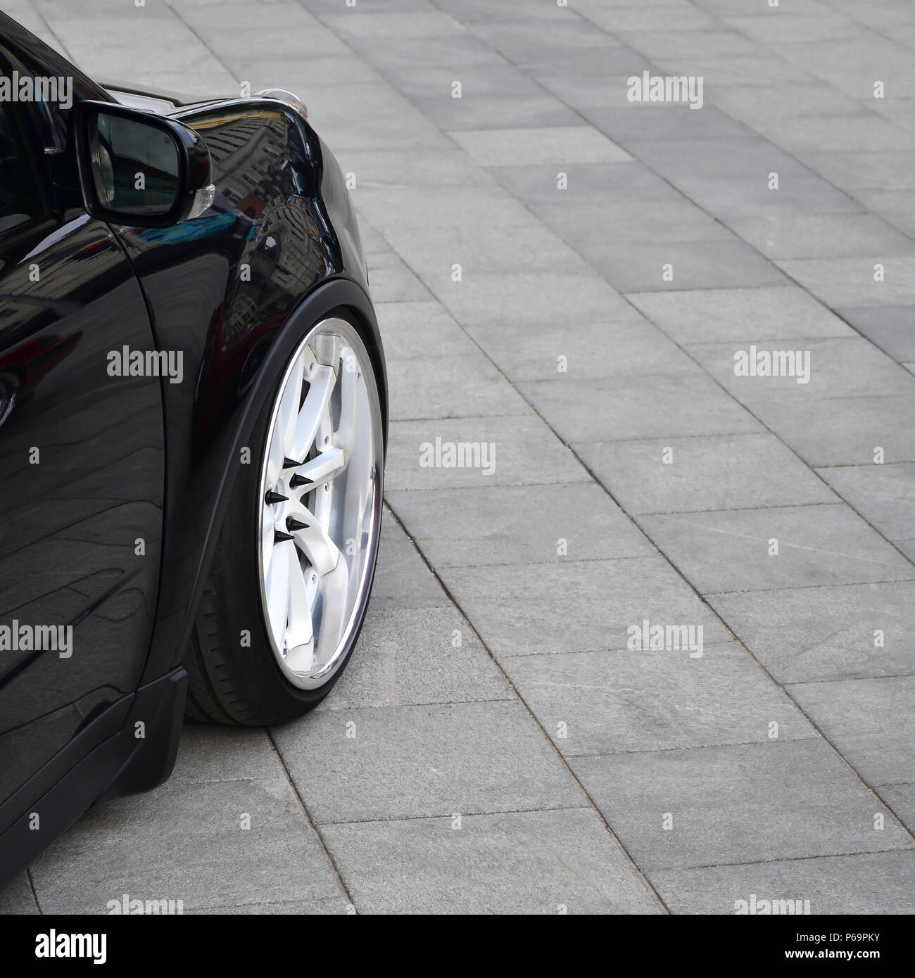 Diagonal view of a black glossy car with white wheels, which stands on ...