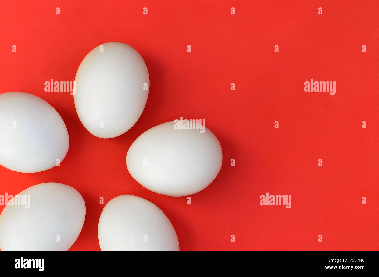 A few white eggs on a bright red background Stock Photo - Alamy