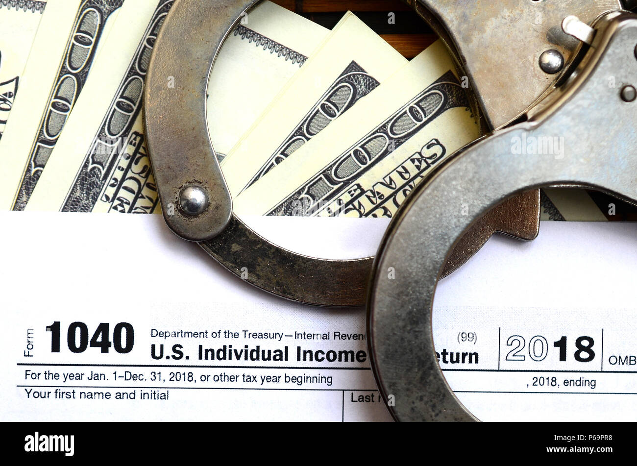 Police handcuffs lie on the tax form 1040. The concept of problems with ...