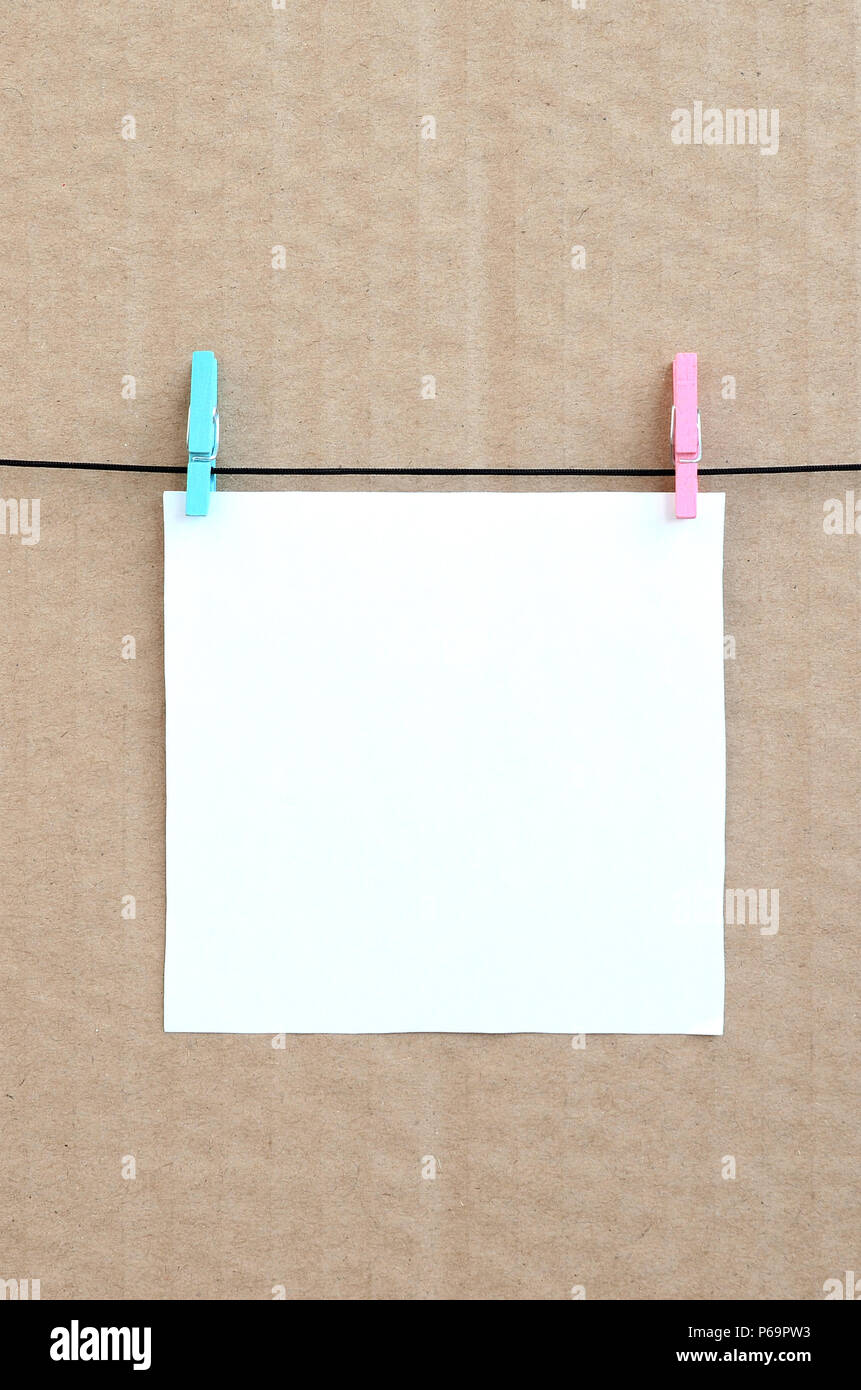 White blank card on rope on a brown cardboard background. Creative ...