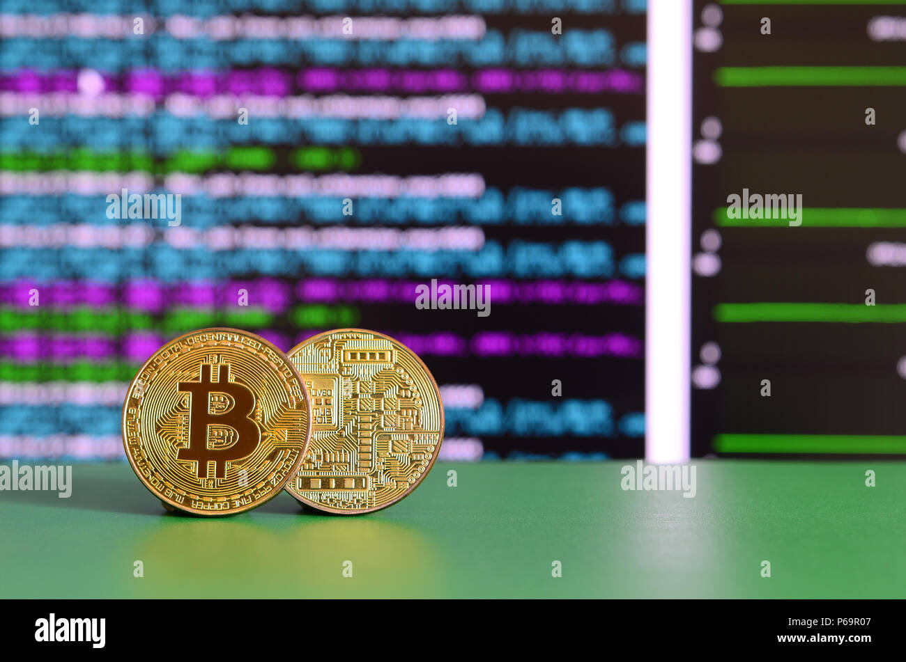 Two gold bitcoins lie on the green surface on the background of the ...