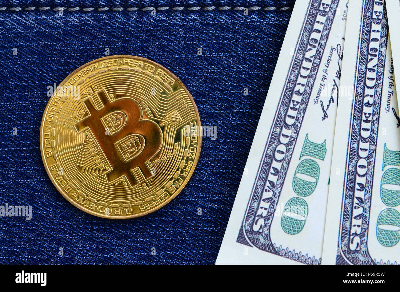 Golden Bitcoin and dollar bills lies on a blue jeans fabric. New ...