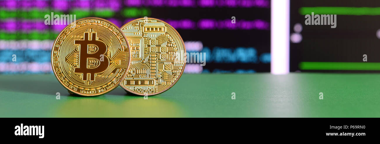 Two gold bitcoins lie on the green surface on the background of the ...