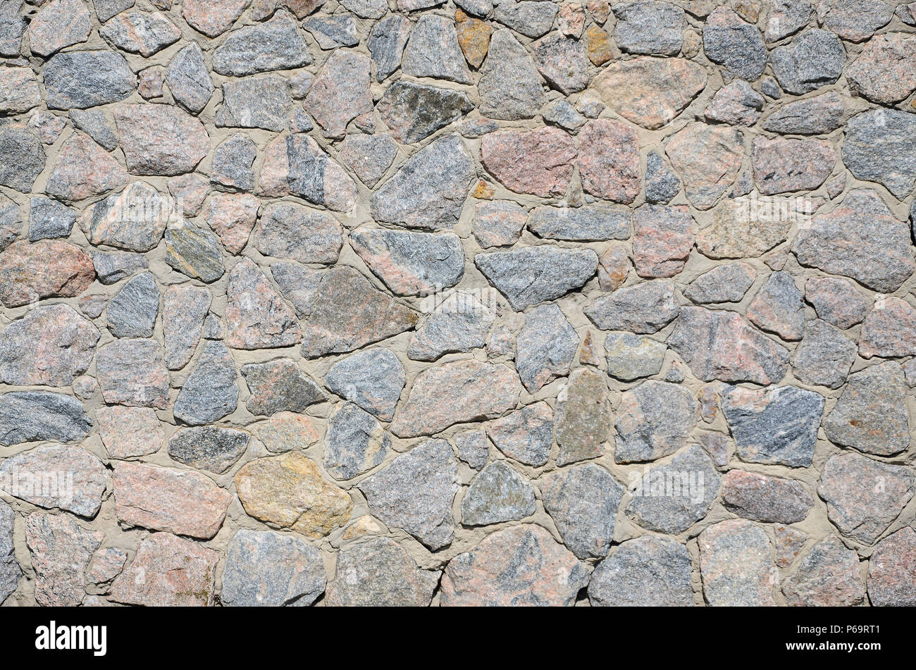 A gray stone wall, cemented between the rounded stones. Background ...